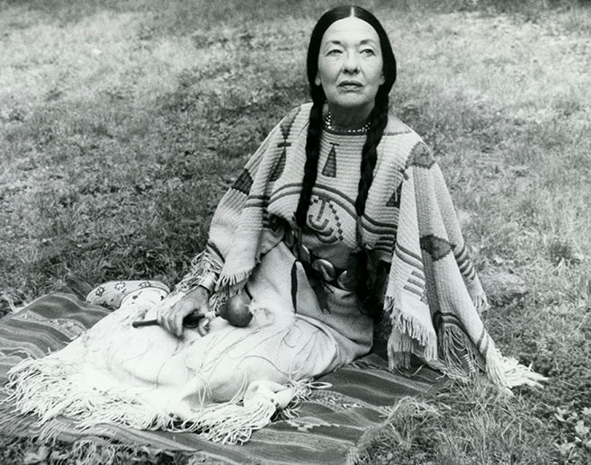Te Ata in Native American dress, sitting on a blanket | Nash Library